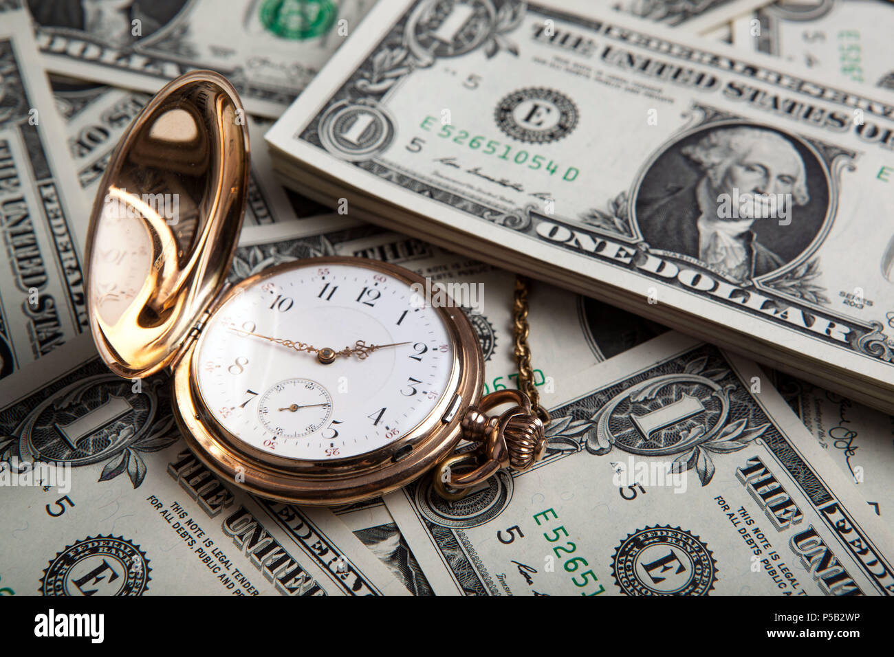 gold watch and dollar bills close up Stock Photo - Alamy