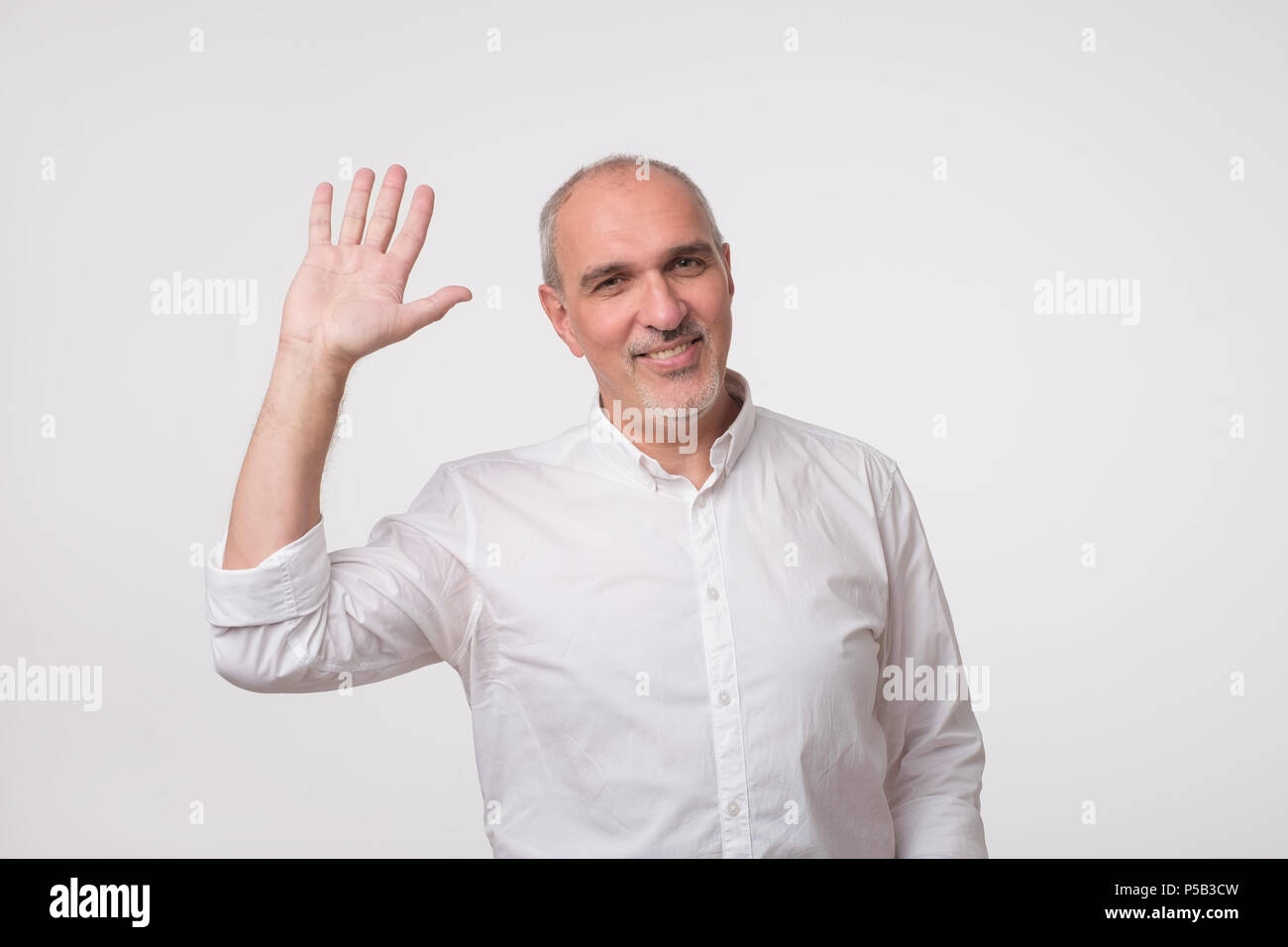 Handsome attractive european man waiving hand in hello gesture while ...