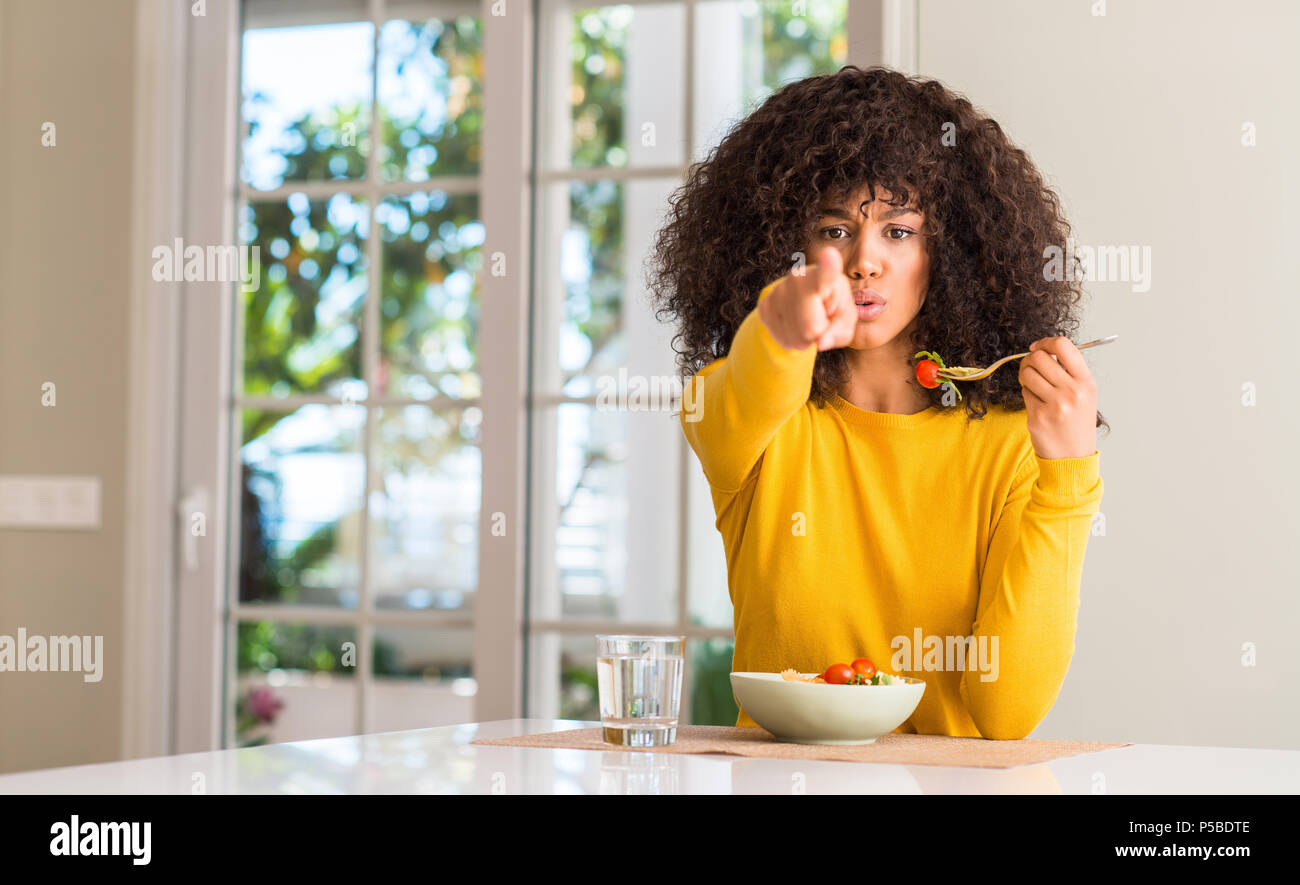 African american woman eating pasta salad pointing with finger to the ...
