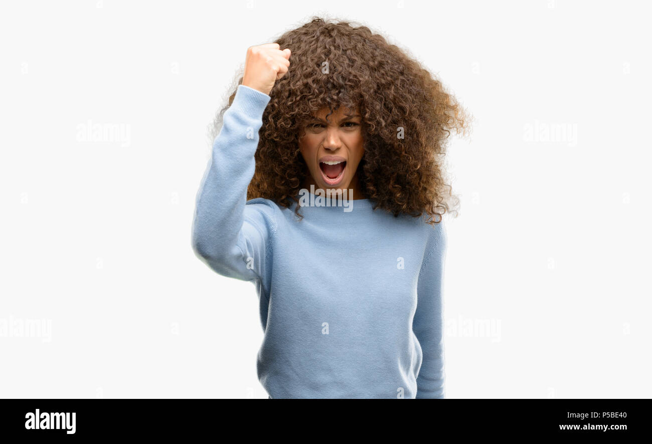 African american woman wearing a sweater angry and mad raising fist ...