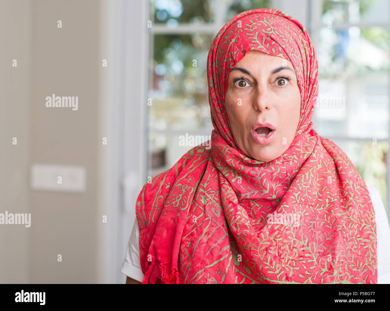 Middle aged muslim woman wearing hijab scared in shock with a surprise ...