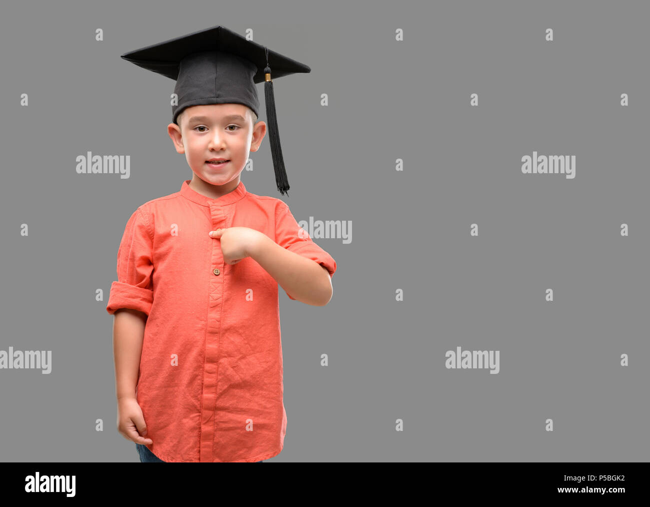 Dark haired little child wearing graduation cap with surprise face ...