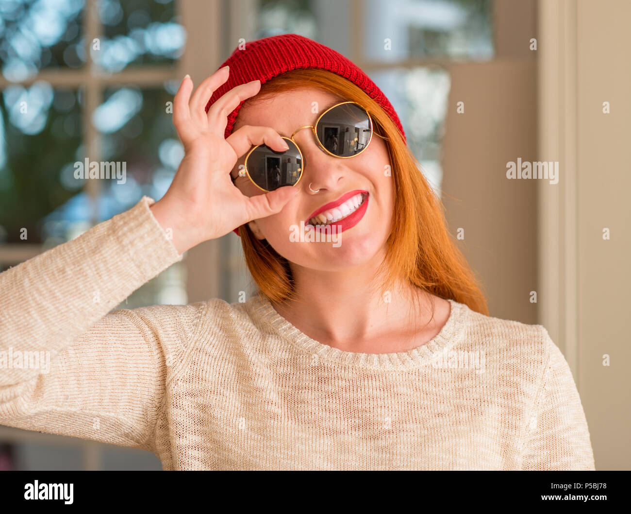 Stylish redhead woman wearing wool cap and sunglasses with happy face ...
