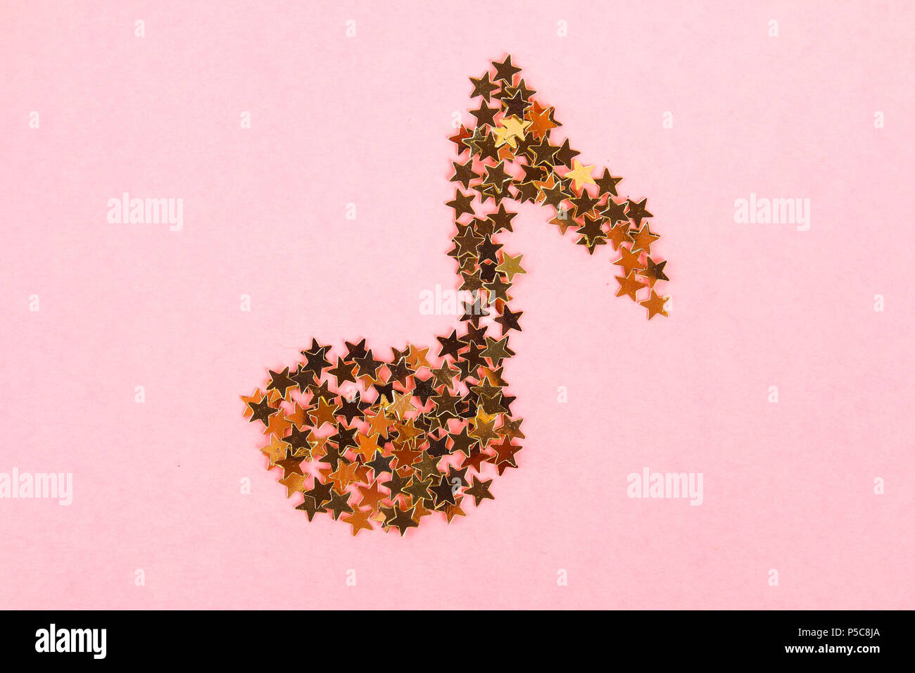 Musical notes of starry golden confetti lying on a pink pastel ...