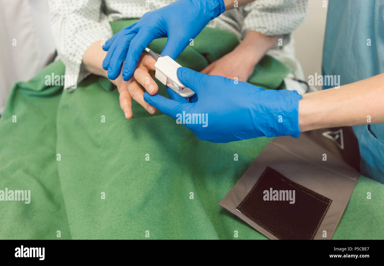 Nurse connecting patient to monitoring device in hospital room Stock ...