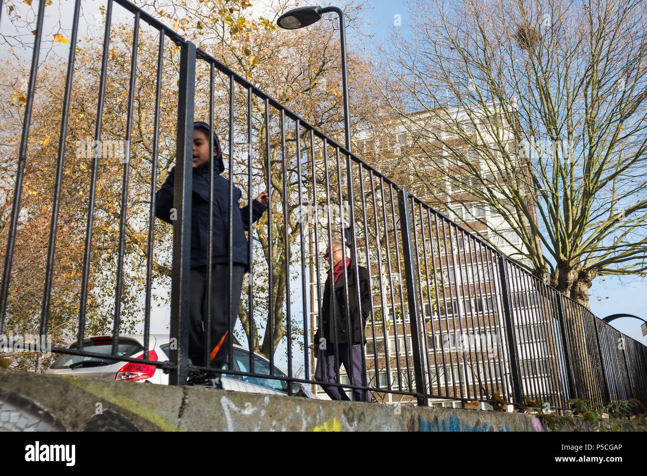 Child holding onto Rail with Father walking along behind on Footpath on ...