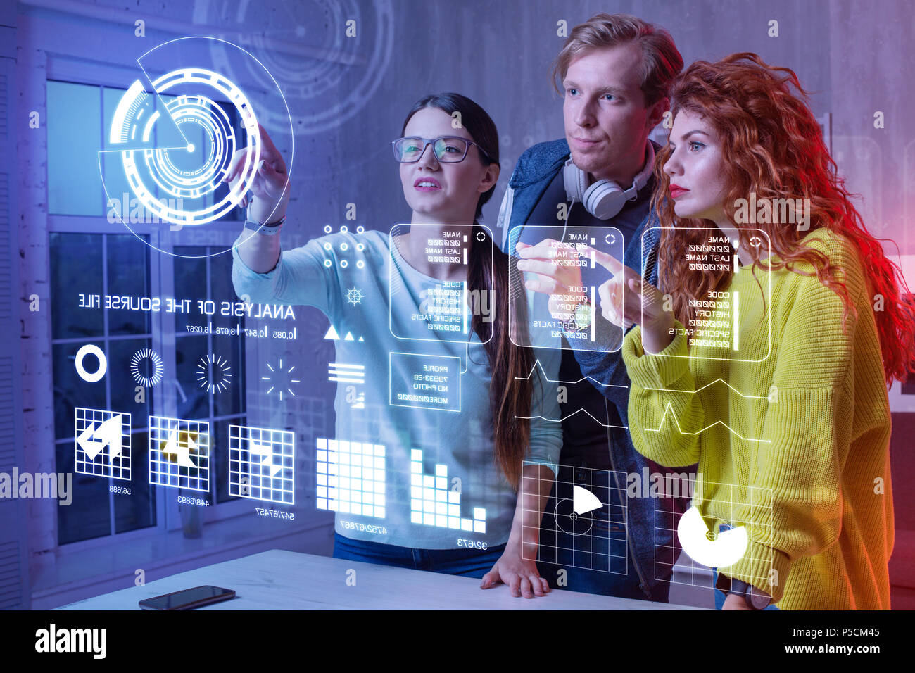 Three friendly people looking at the screen and thinking Stock Photo ...