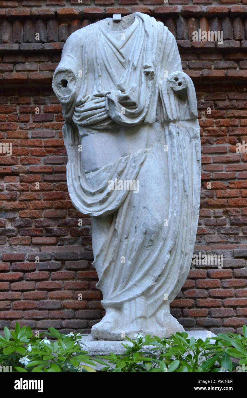 A classic headless marble sculpture with a stone wall behind in the ...