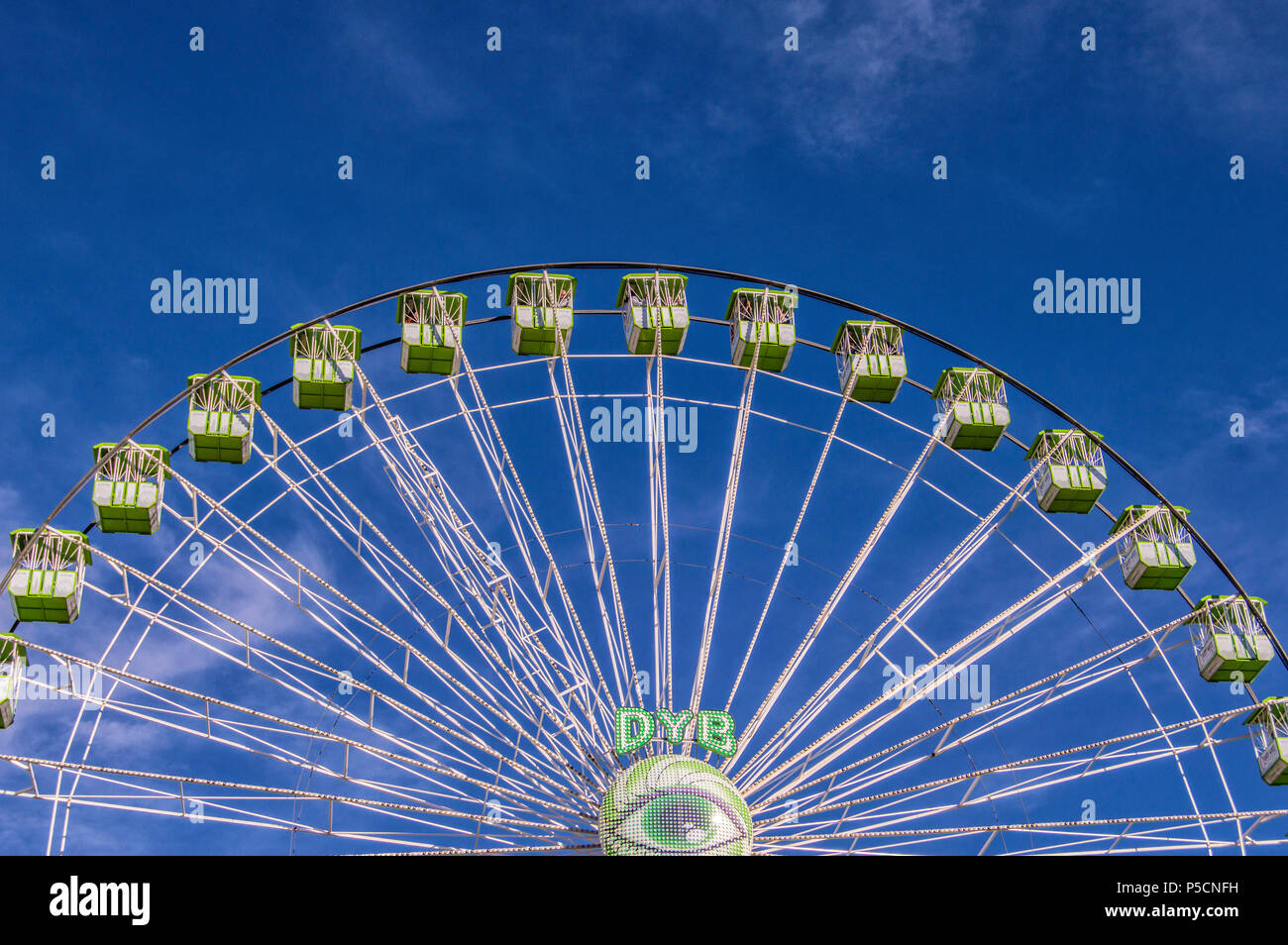 Part of a ferris wheel in horizontal with blue sky background at a fair ...