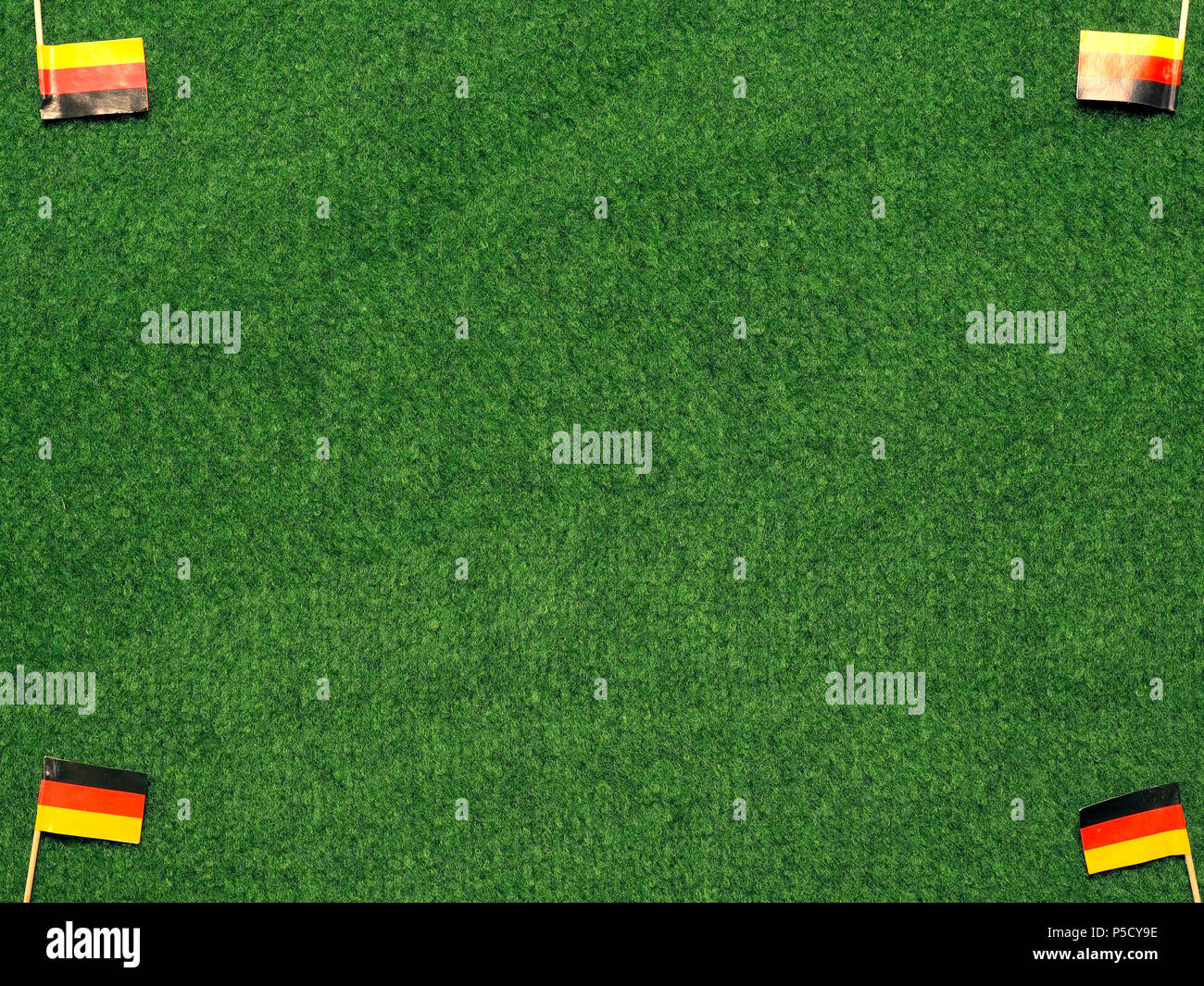 Four small German flags on green grass background with space for text ...