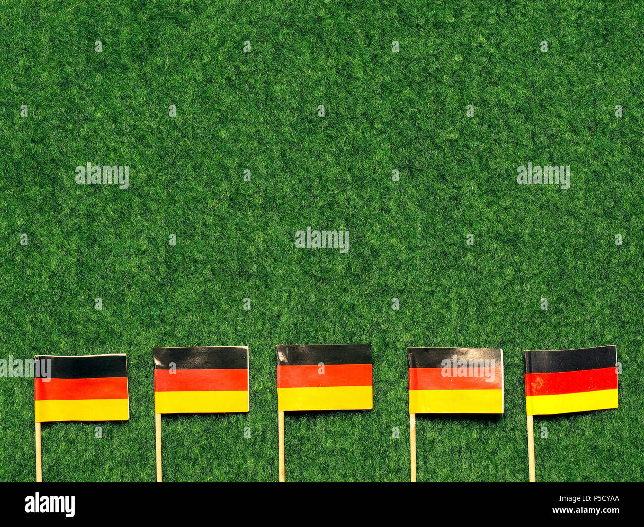 Small German flags on a green grass background with space for text or ...
