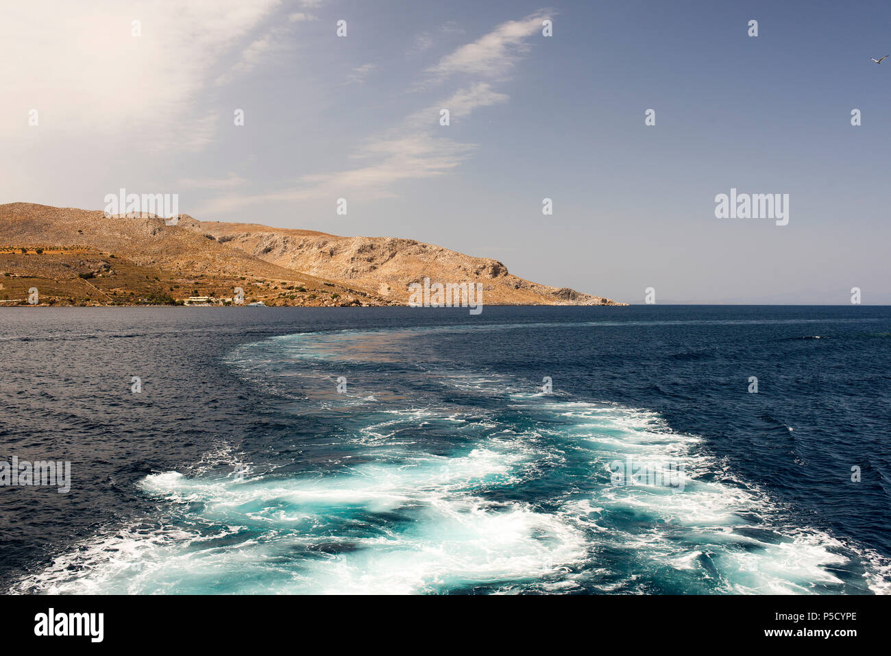 A view of a Greek island and waves and splashes from catamaran in the ...
