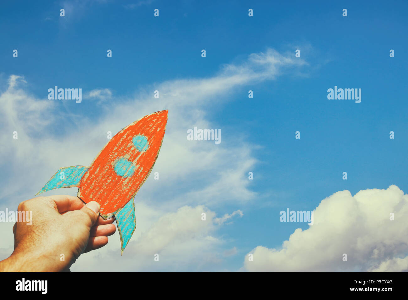 image of male hand holding a rocket against the sky. imagination and ...
