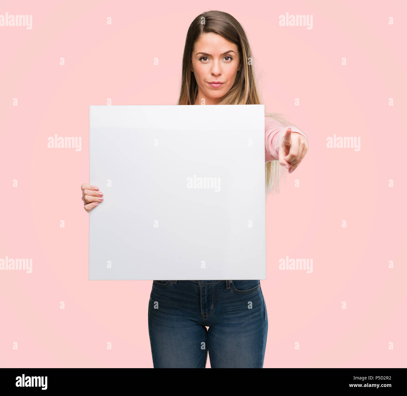 Beautiful young woman holding advertising banner pointing with finger ...