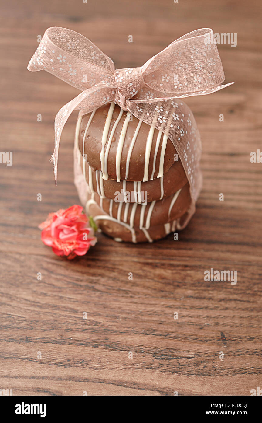 A stack of chocolate covered biscuits tied with a pink ribbon and an ...