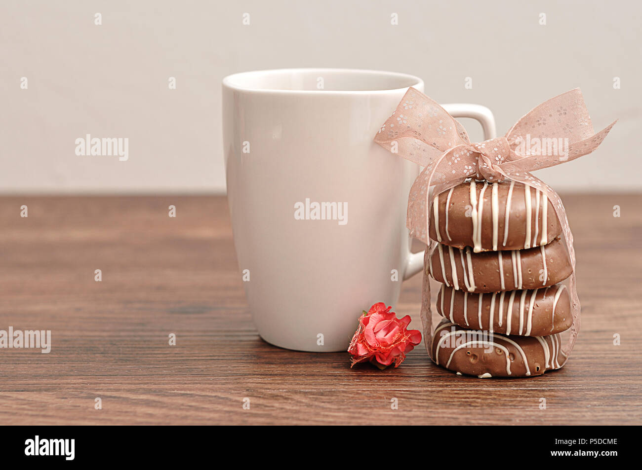 A stack of chocolate covered biscuits tied with a pink ribbon, an ...