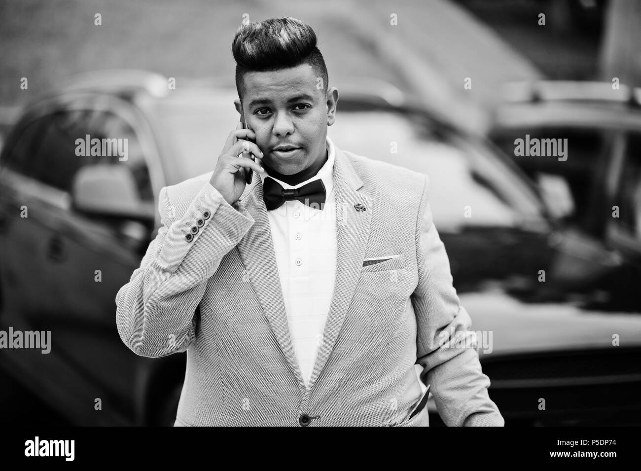 Stylish arabian man in jacket, bow tie against black suv car. Arab rich ...