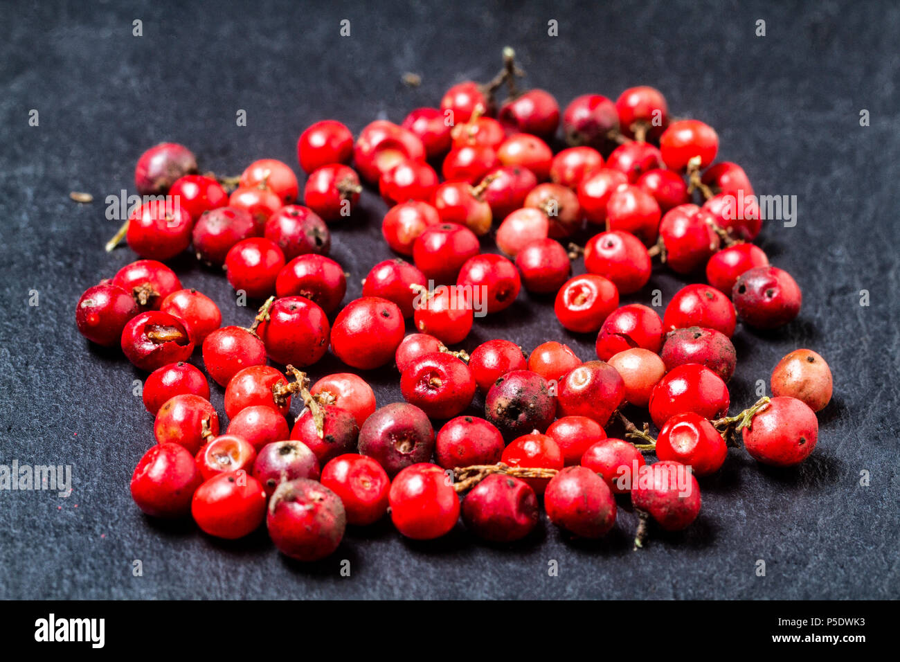 Pink pepper, also known as aroeira or Brazilian pepper, on a slate ...