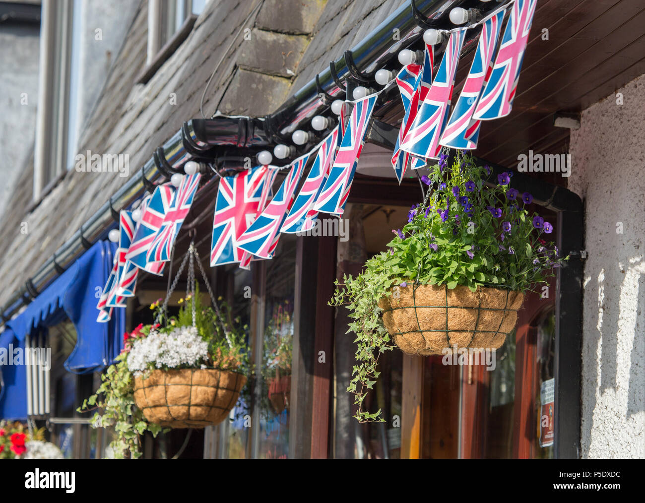 A row of Union Jack Flags and two hanging baskets outside a public ...