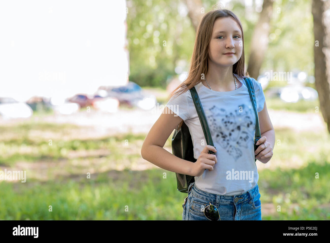 Girl schoolgirl. Summer in nature. Behind him is a backpack. Free space ...