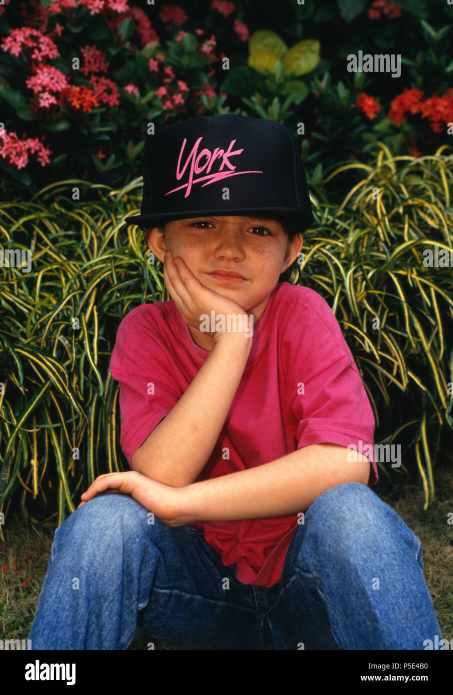 Lifestyle. Children. Young girl sitting outdoors, wearing a cap. New ...