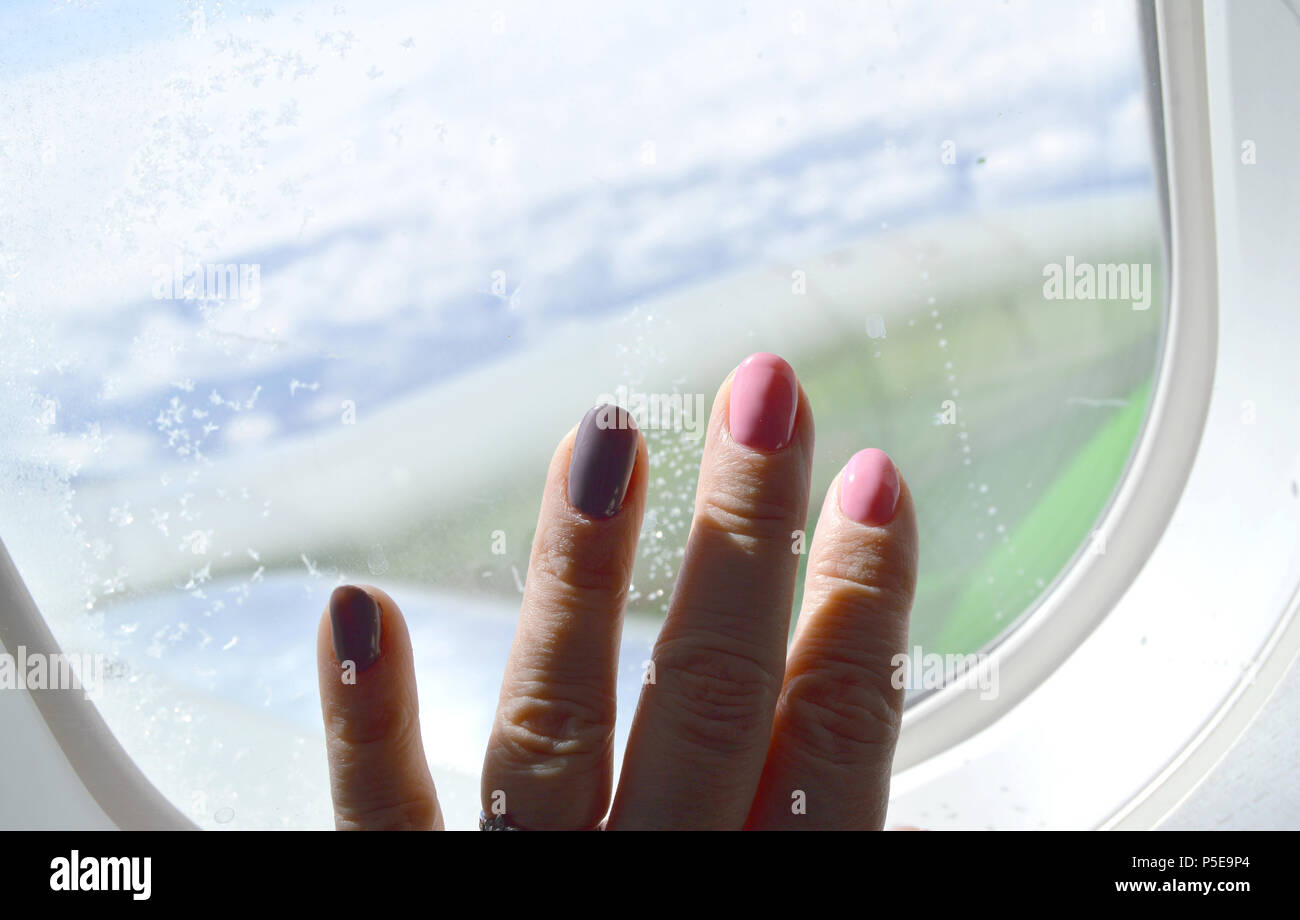 Female hand on the background of the window in the plane. Clouds and ...