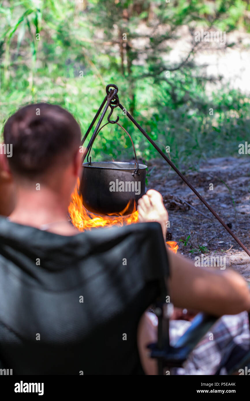 Tourist pot hanging over the fire on a tripod. Cooking in the campaign ...