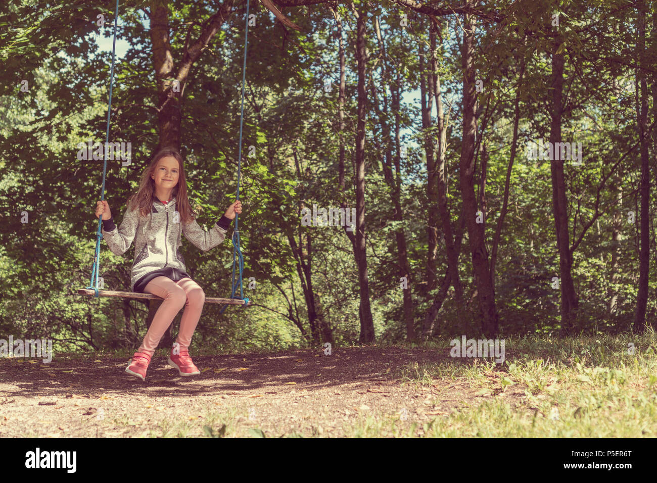 Cute girl swinging on a tree swings Stock Photo - Alamy