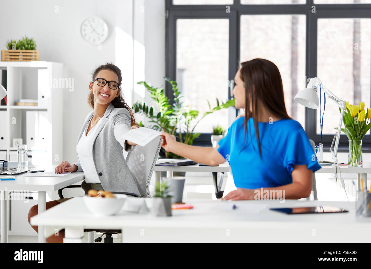 businesswomen giving each other papers at office Stock Photo - Alamy