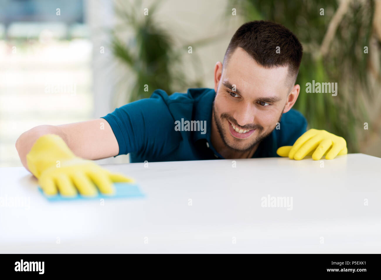 smiling man cleaning table with cloth at home Stock Photo - Alamy