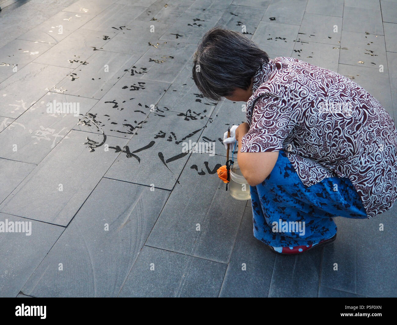 Older woman practicing calligraphy and writing " le ye fu ren" meaning ...