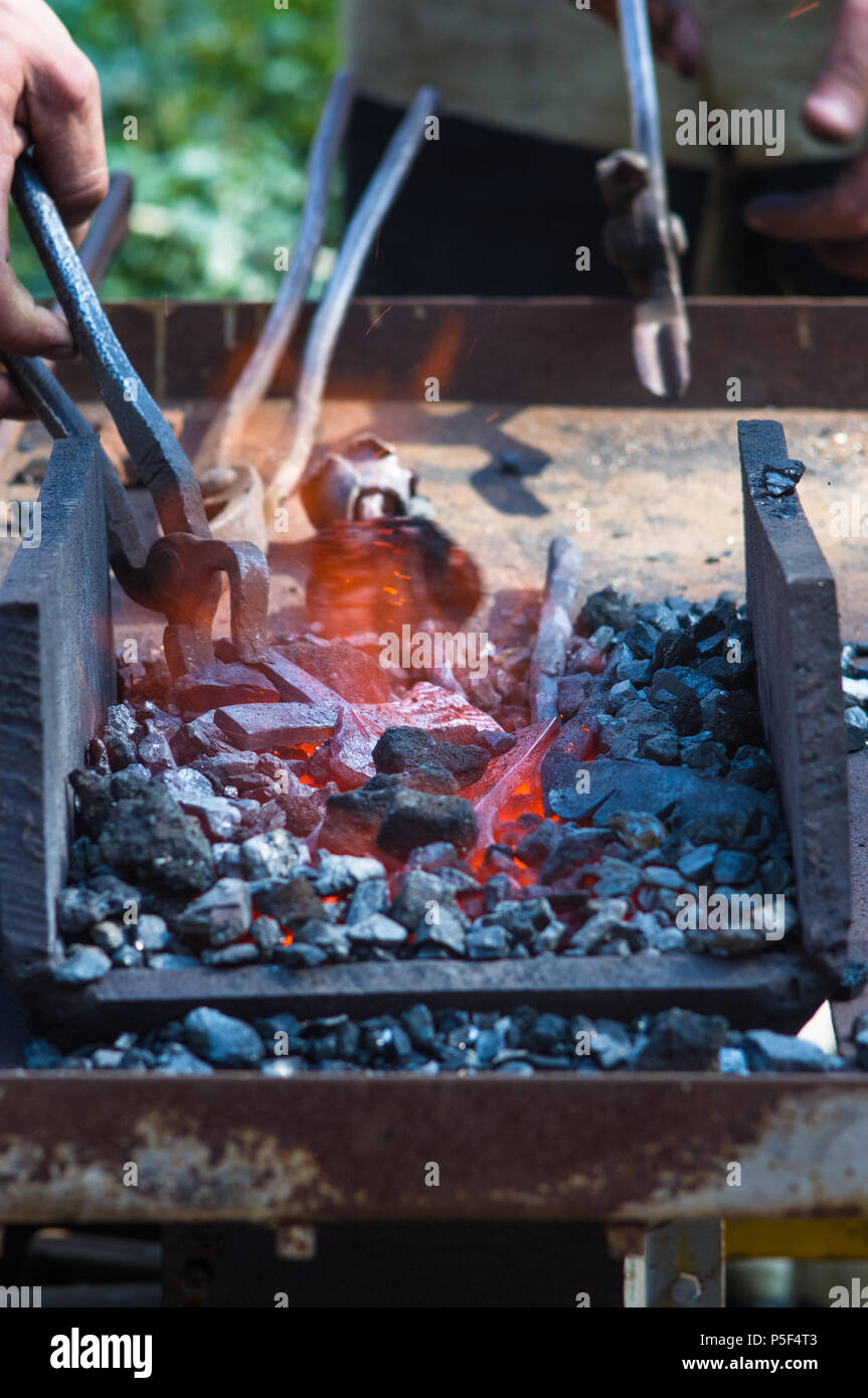 blacksmith furnace with burning coals, tools, and glowing hot metal ...