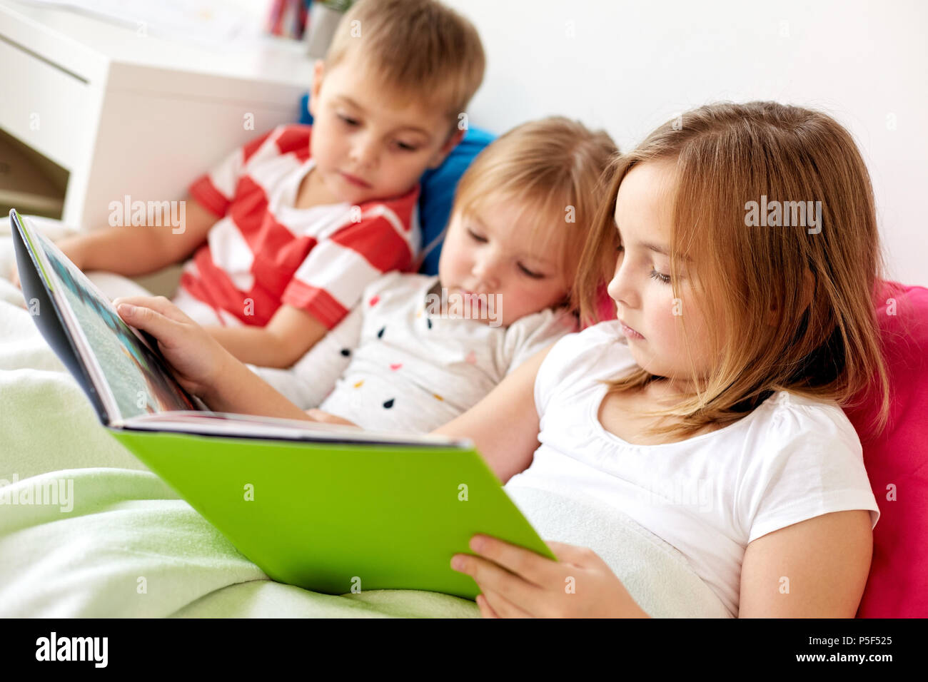 little kids reading book in bed at home Stock Photo - Alamy