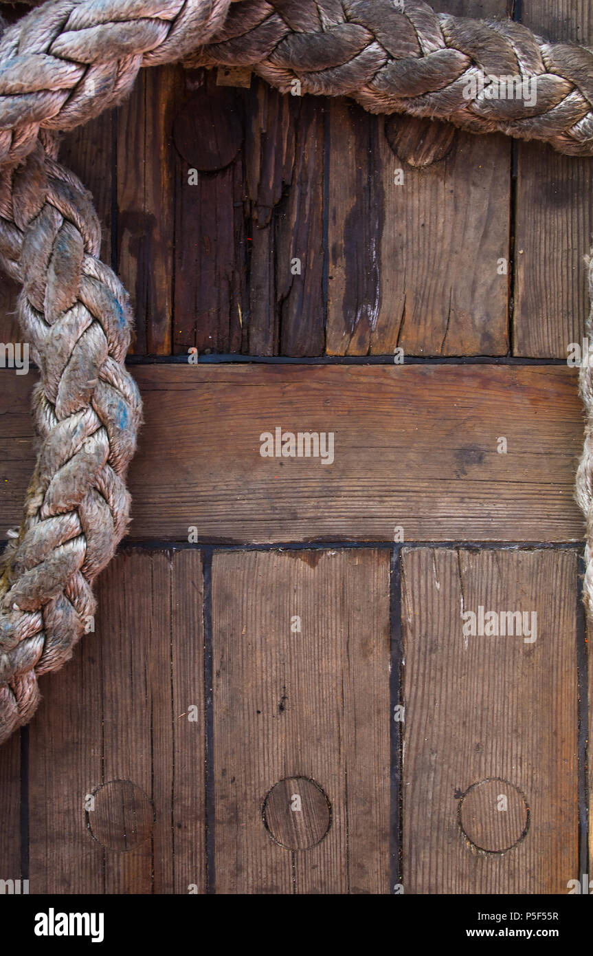Old braided rope on the wooden deck of a sea boat, cleats, anchor ...