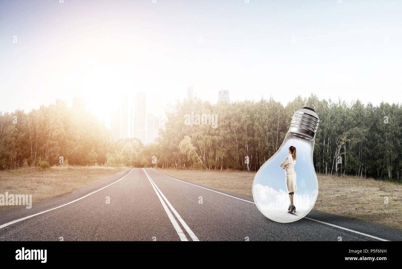 Young businesswoman trapped inside of light bulb on asphalt road Stock ...