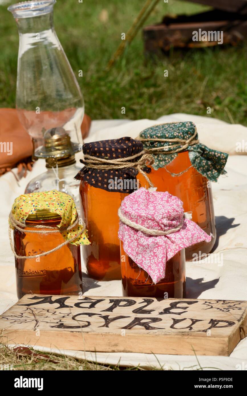 Glass jars, with fabric toppers held on by string, of maple syrup ...