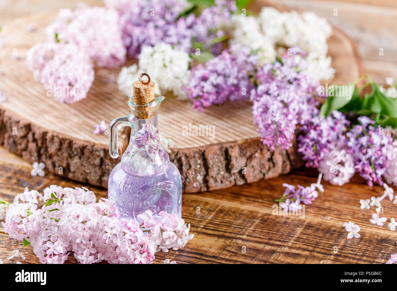 Lilac flowers and tincture in a glass beautiful bottle on a wooden cut ...