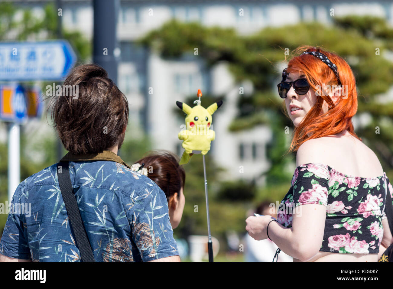 Tourist group following tour guide with a Pokemon stick Stock Photo - Alamy