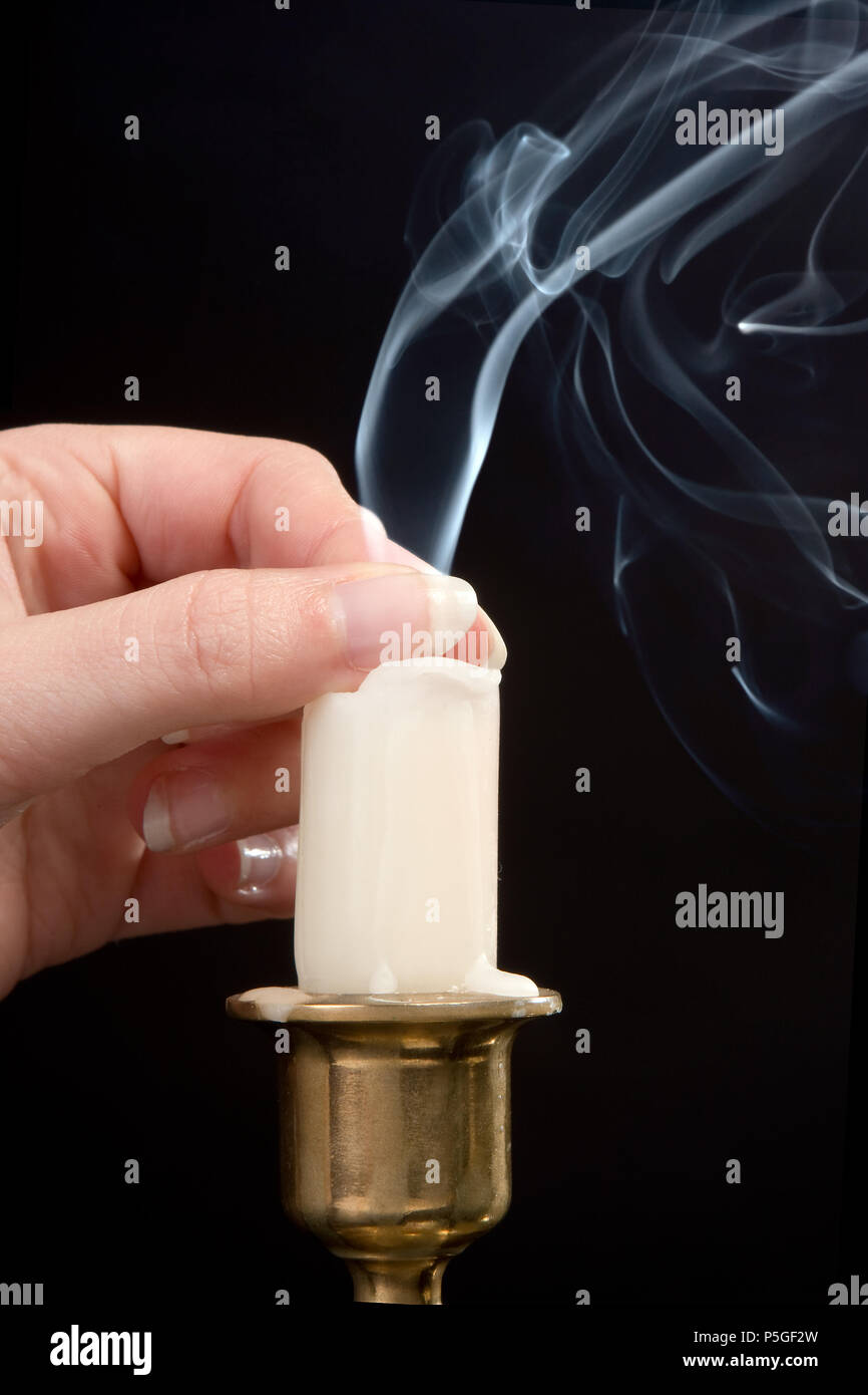 Female hand extinguishing the flame of a candle Stock Photo - Alamy