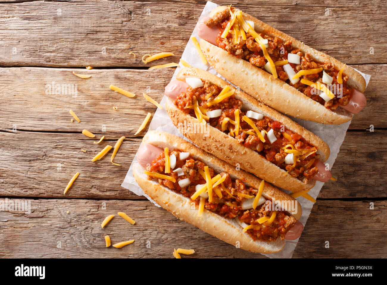 Traditional American chili hot dogs with cheddar cheese, onion and ...