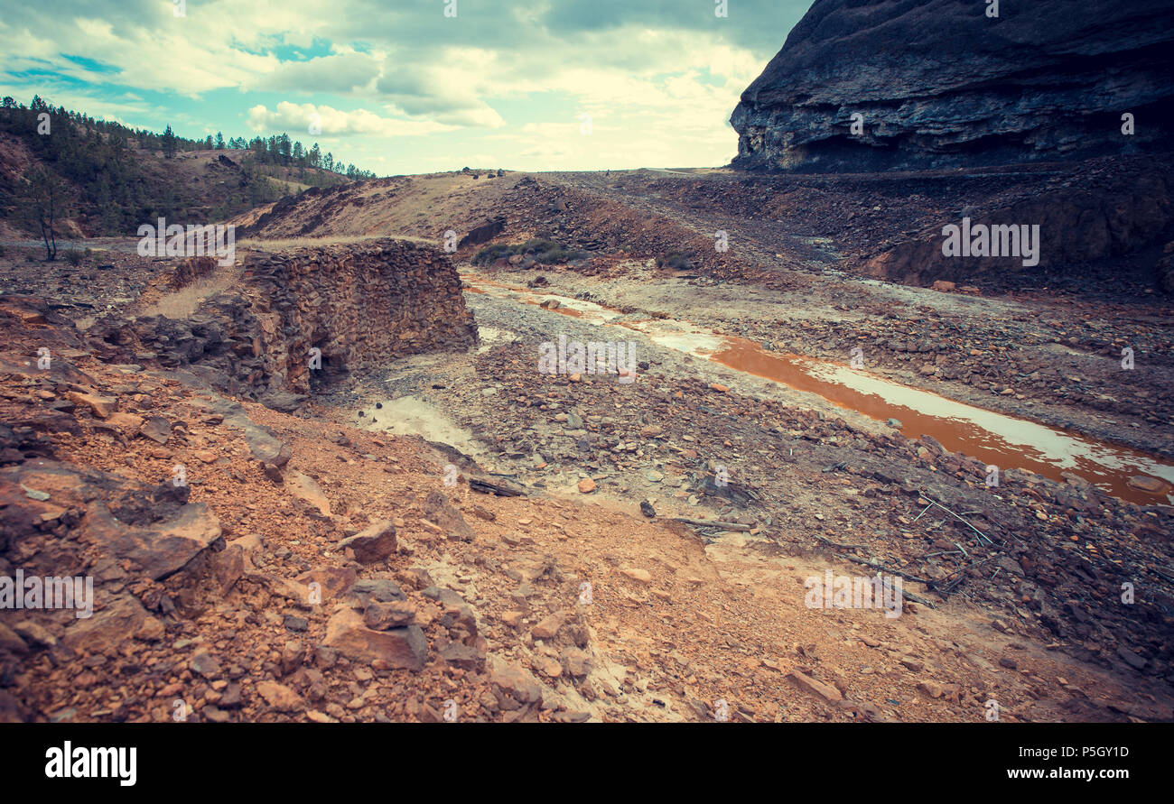 Old stone wall on the banks of the red river (Riotinto) of acid waters ...