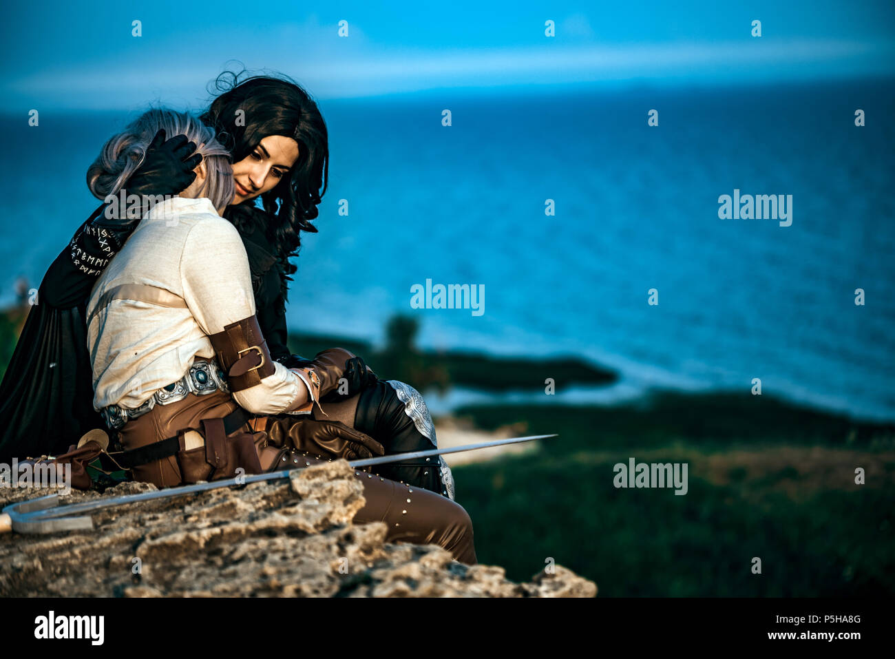 Fantasy cosplay two beautiful girls hug on cliff Stock Photo - Alamy