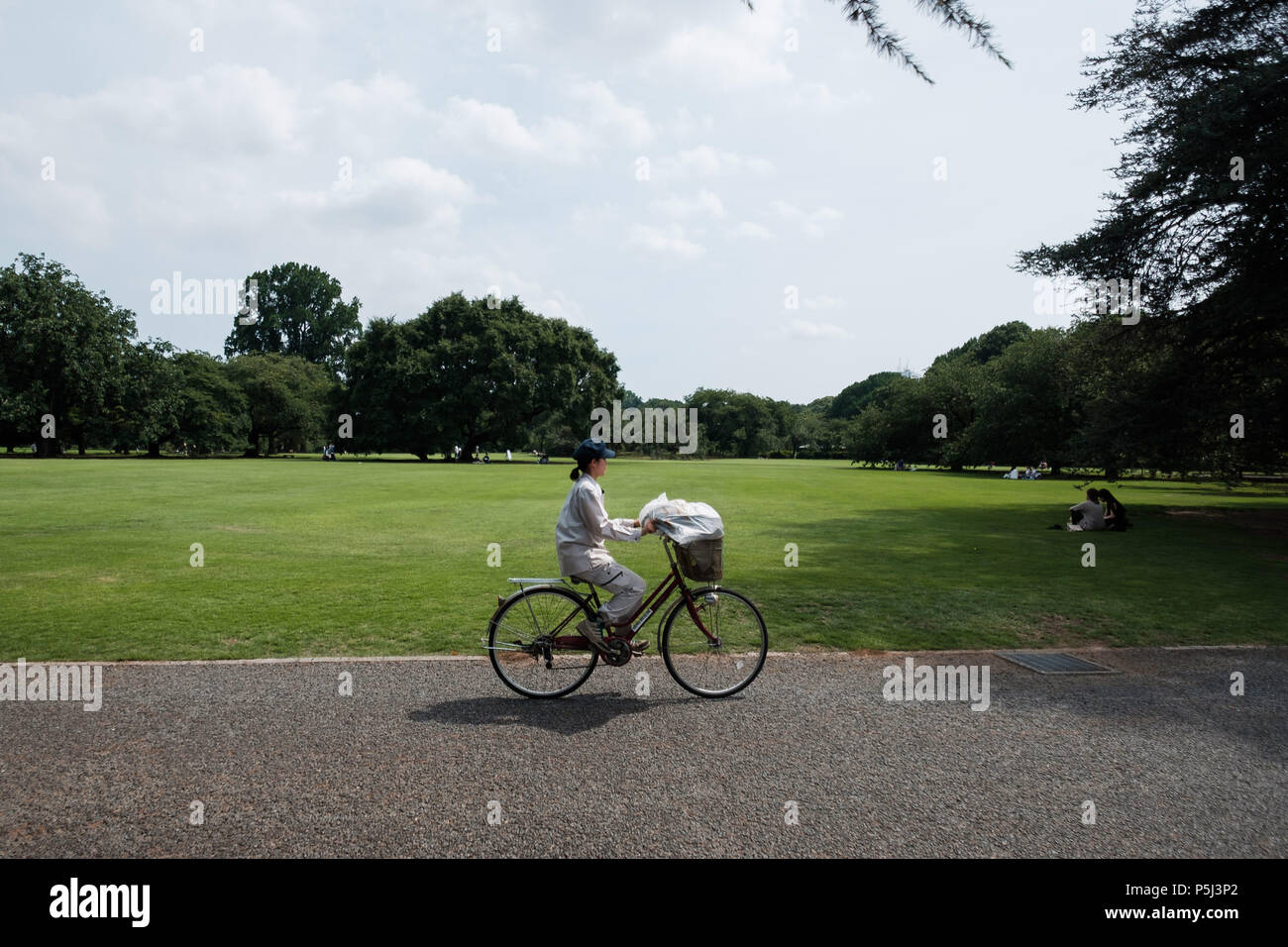 Park's staff rides a bike under a sunny weather in Shinjuku Gyoen park ...