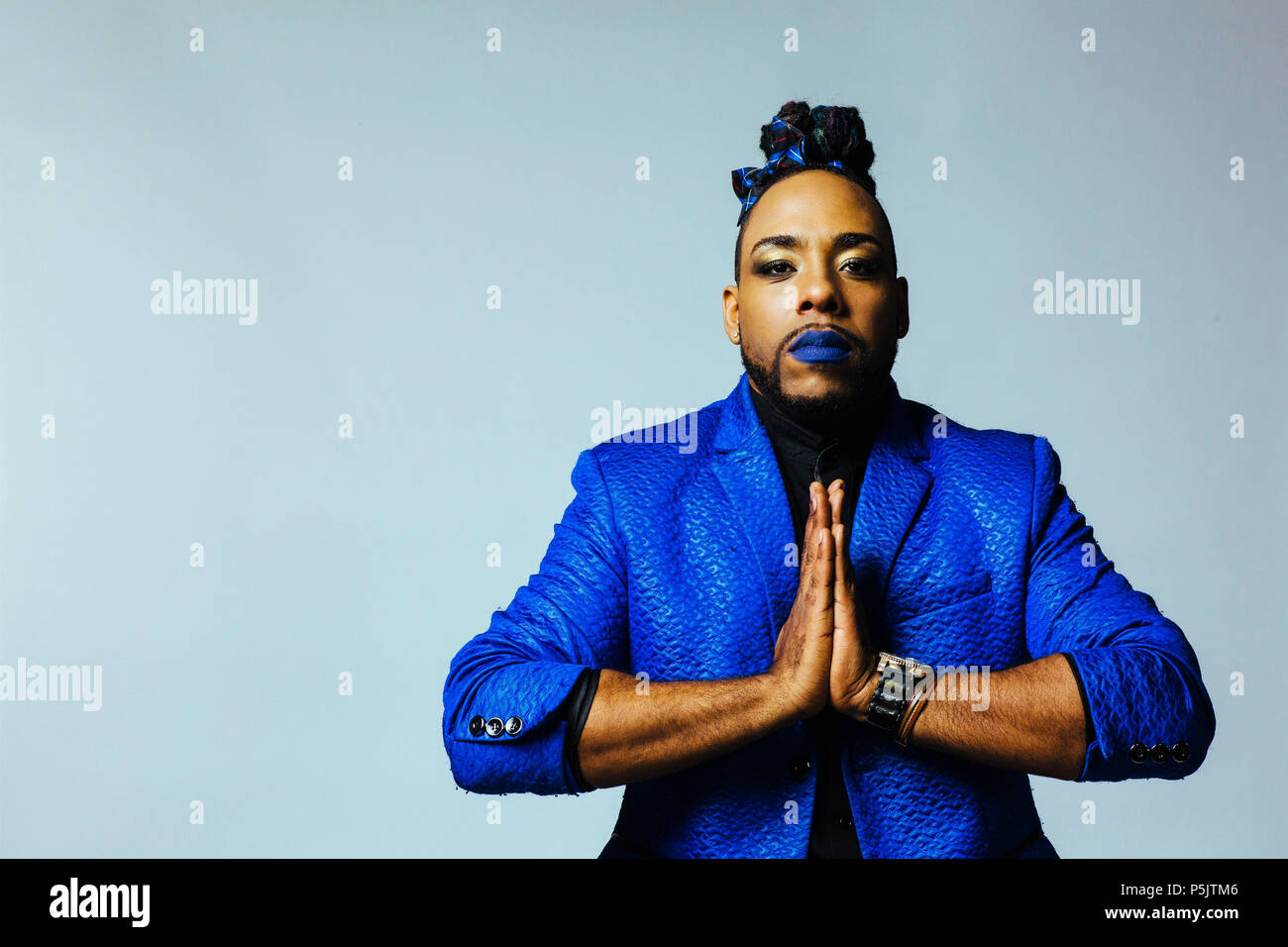 Portrait of a man in blue jacket and blue lips and hands together in ...