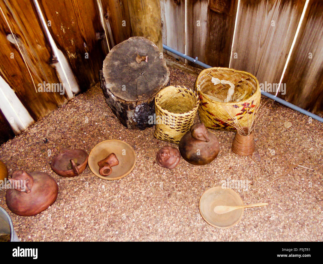 Interior of a Native American summer house with pottery, bowls, clay pipes, and baskets and a ...
