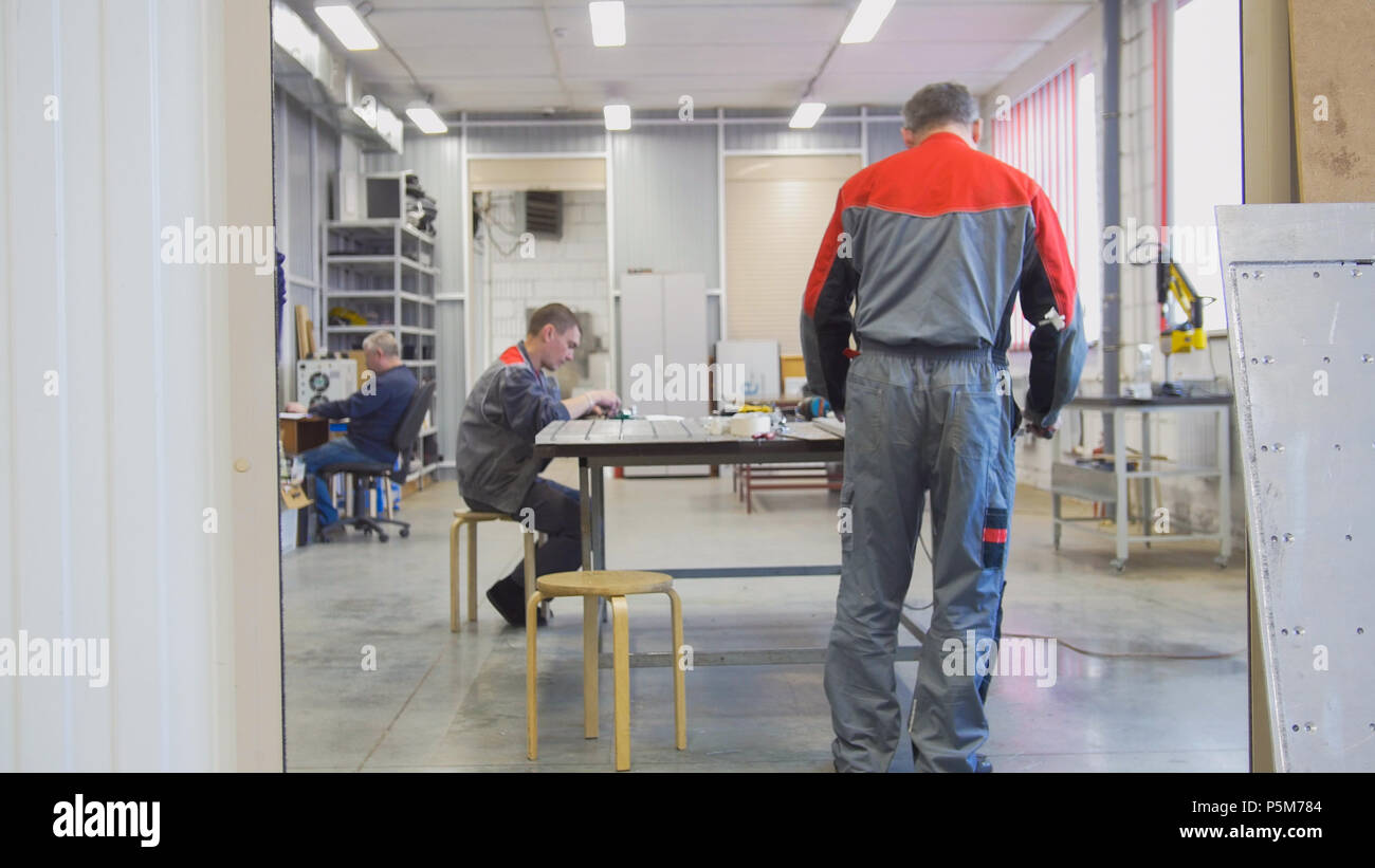 Male workers at manufacturing of CNC machines cleaning the workspace ...