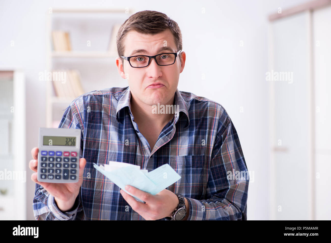 Young man frustrated at his house and tax bills Stock Photo - Alamy