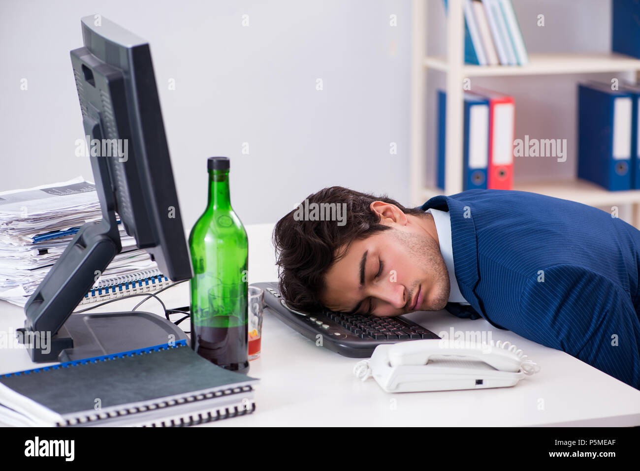 Young businessman employee drinking in the office at desk Stock Photo ...