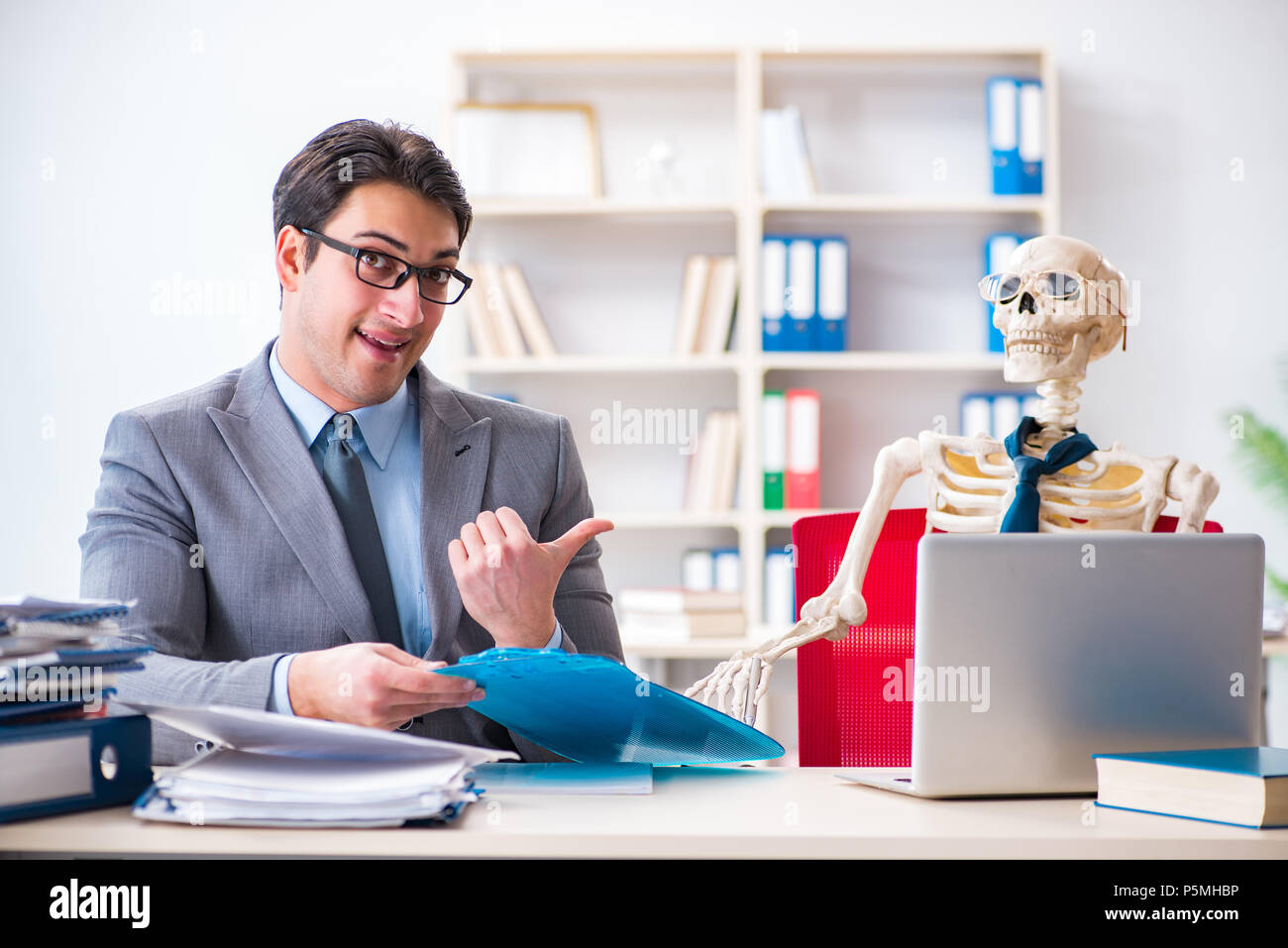 Businessman working with skeleton in office Stock Photo - Alamy