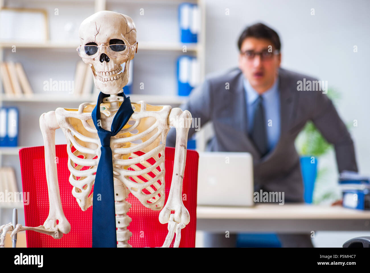 Businessman working with skeleton in office Stock Photo - Alamy